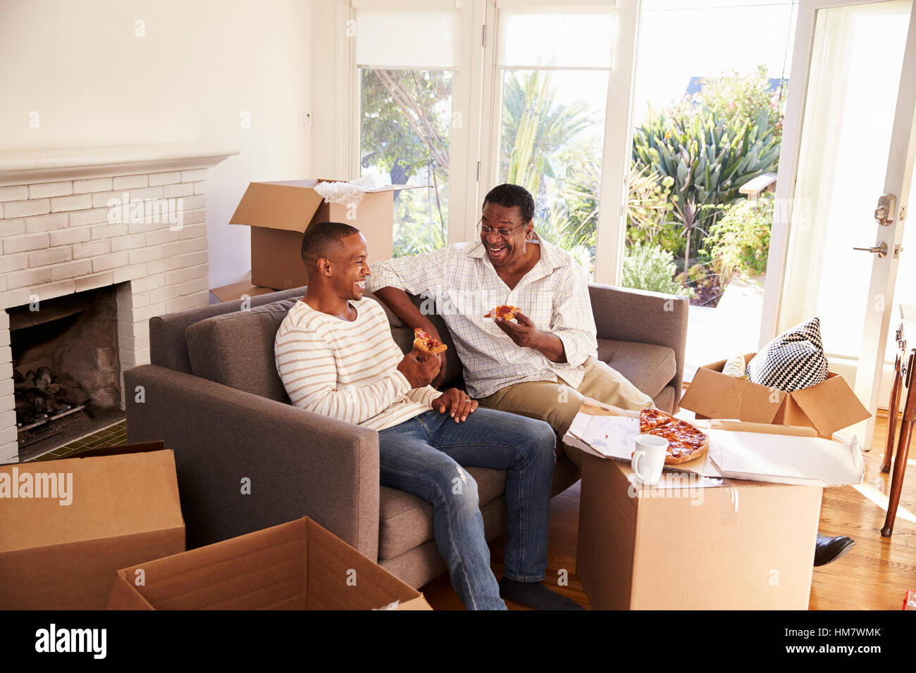 Father And Adult Son Take A Break With Pizza On Moving Day Stock Photo ...