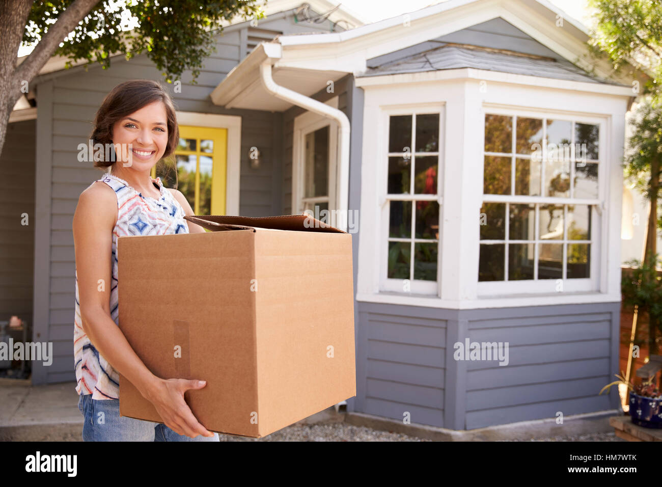 Woman Carrying Box Into New Home On Moving Day Stock Photo - Alamy