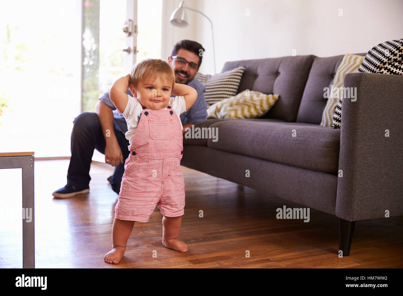 Father Watching Baby Daughter Take First Steps At Home Stock Photo - Alamy