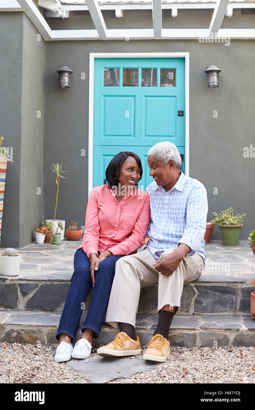 Senior couple sit on steps outside their house, vertical Stock Photo ...