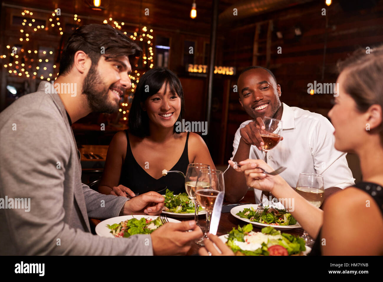 Four friends enjoying dinner and drinks at a restaurant Stock Photo - Alamy