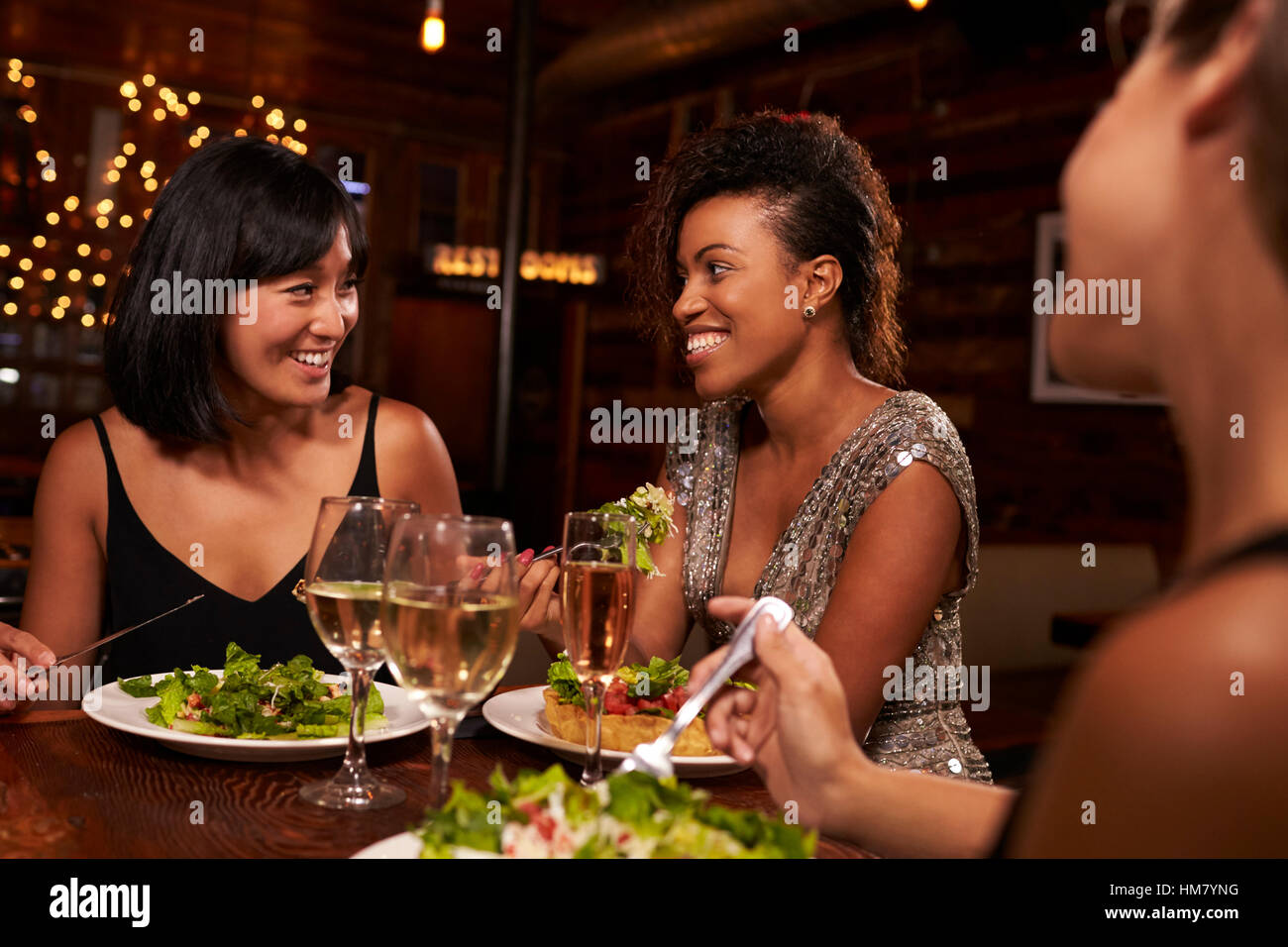 Three female friends enjoying dinner at a restaurant Stock Photo - Alamy