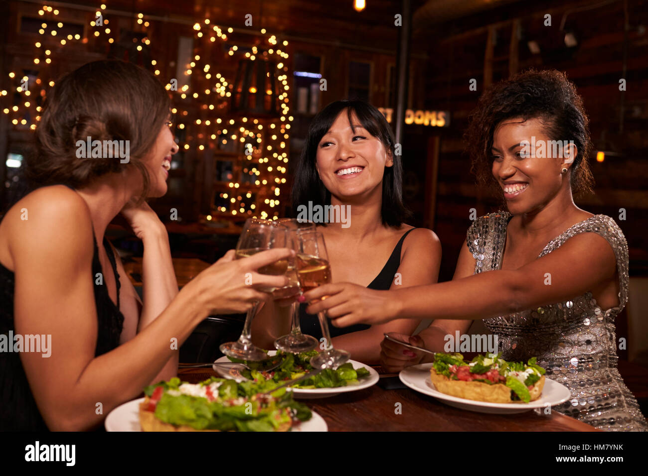 Three female friends make a toast over dinner at restaurant Stock Photo ...