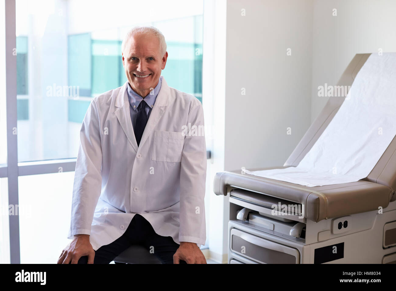 Portrait Of Male Doctor Wearing White Coat In Exam Room Stock Photo - Alamy