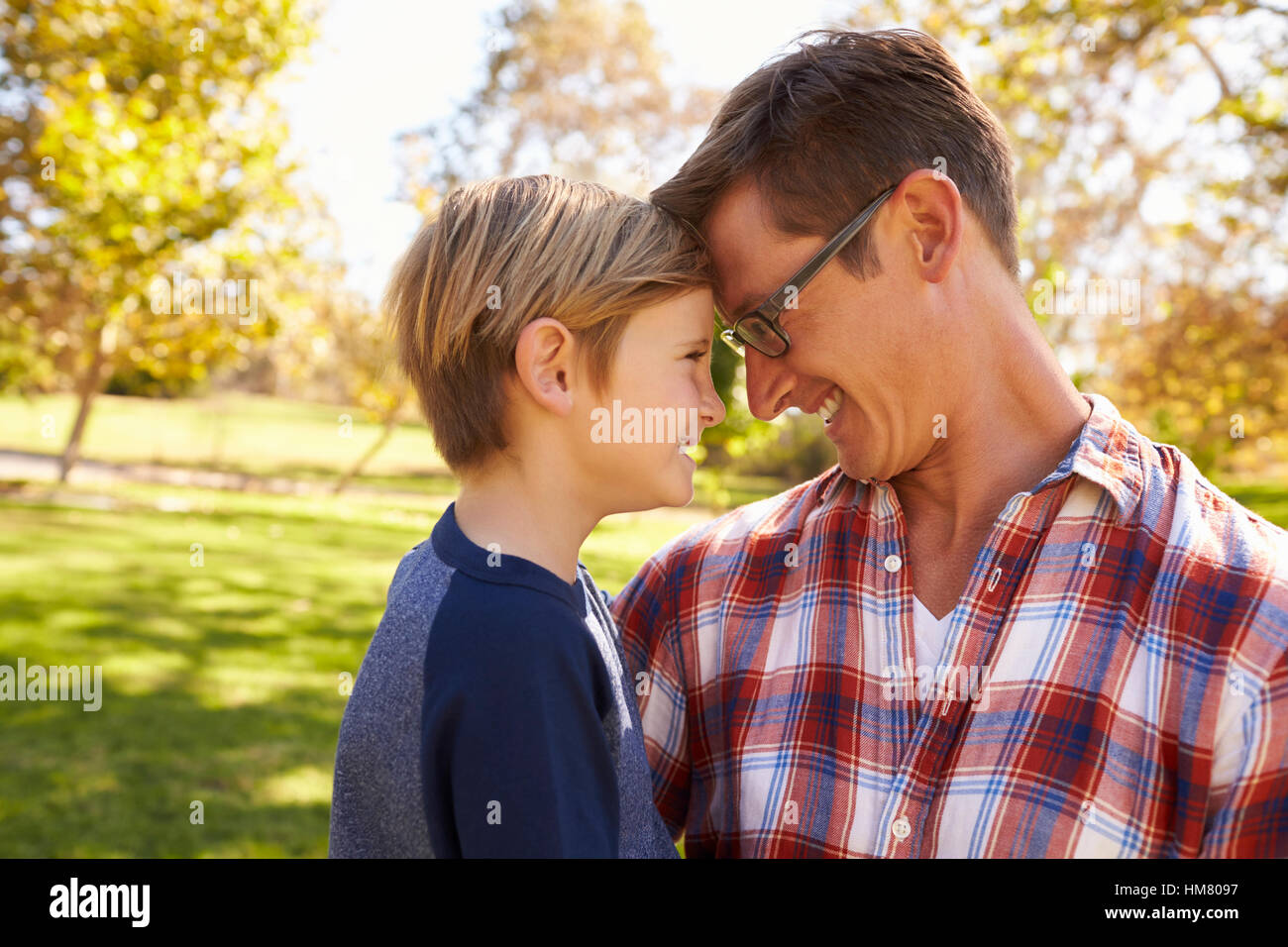 Father and young son in a park, heads together, side view Stock Photo ...