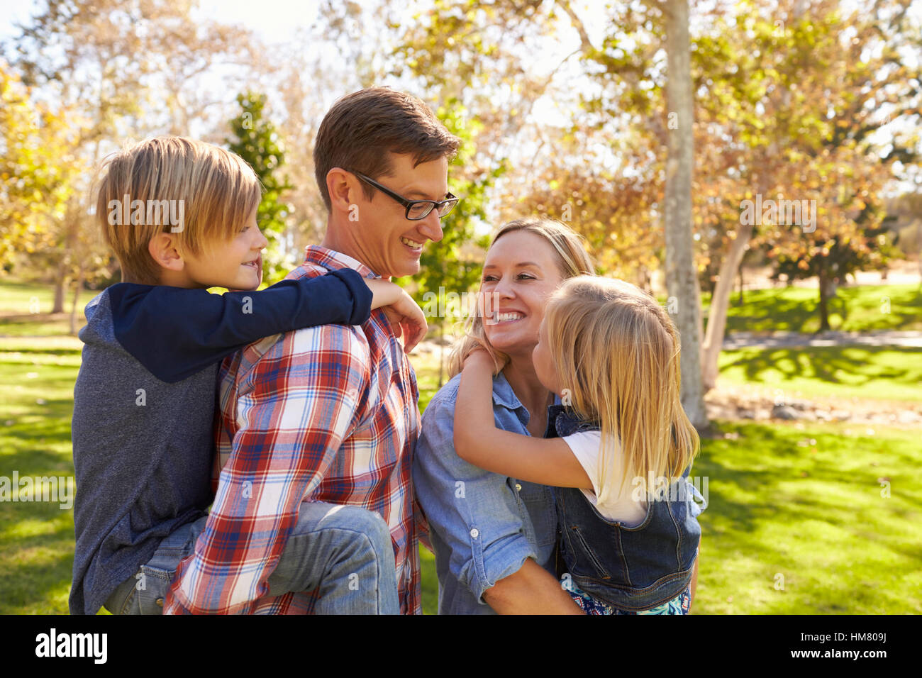 Parents carrying their two young children in a park Stock Photo - Alamy