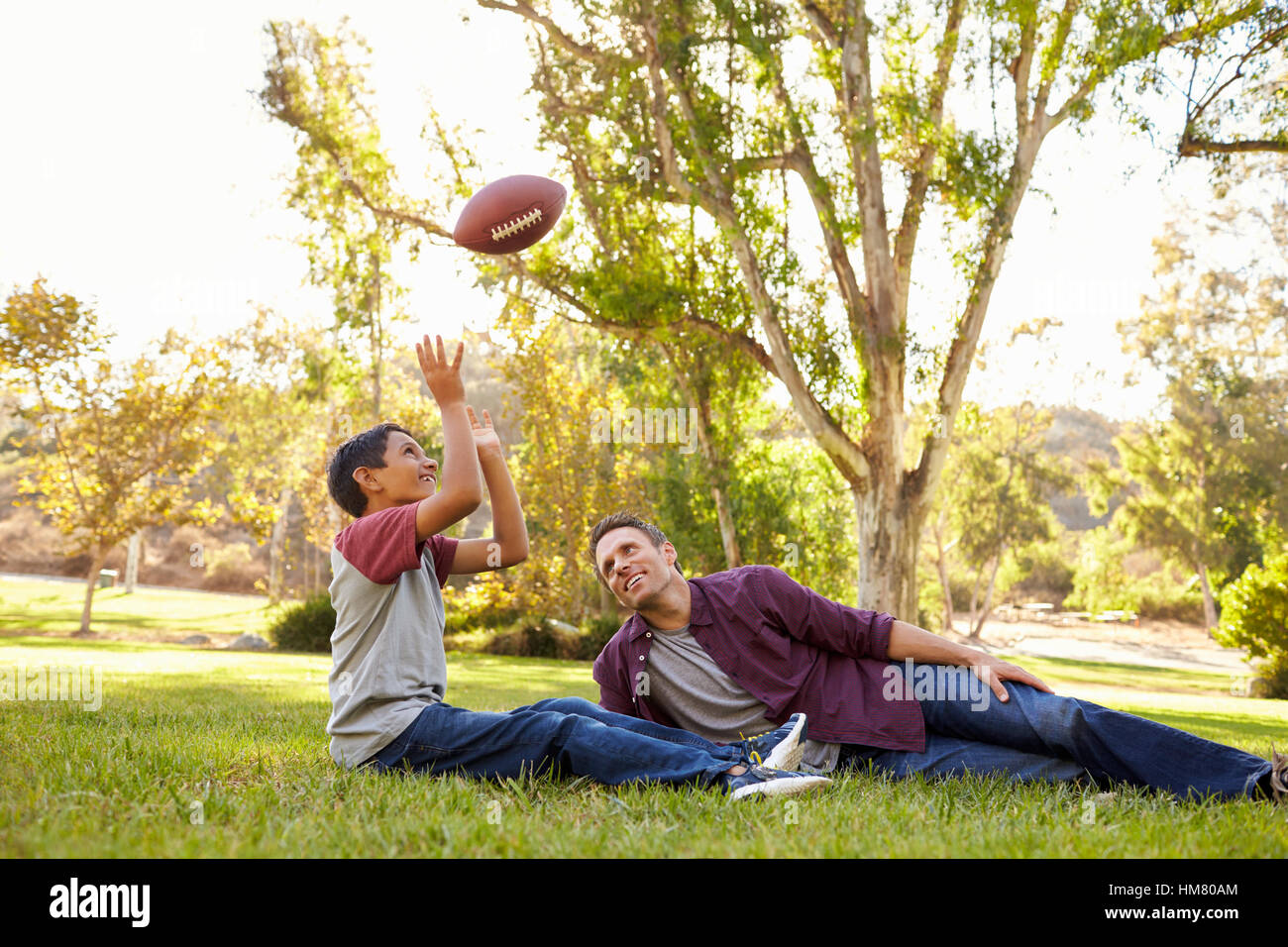 Father and son relax, throwing American football in a park Stock Photo ...