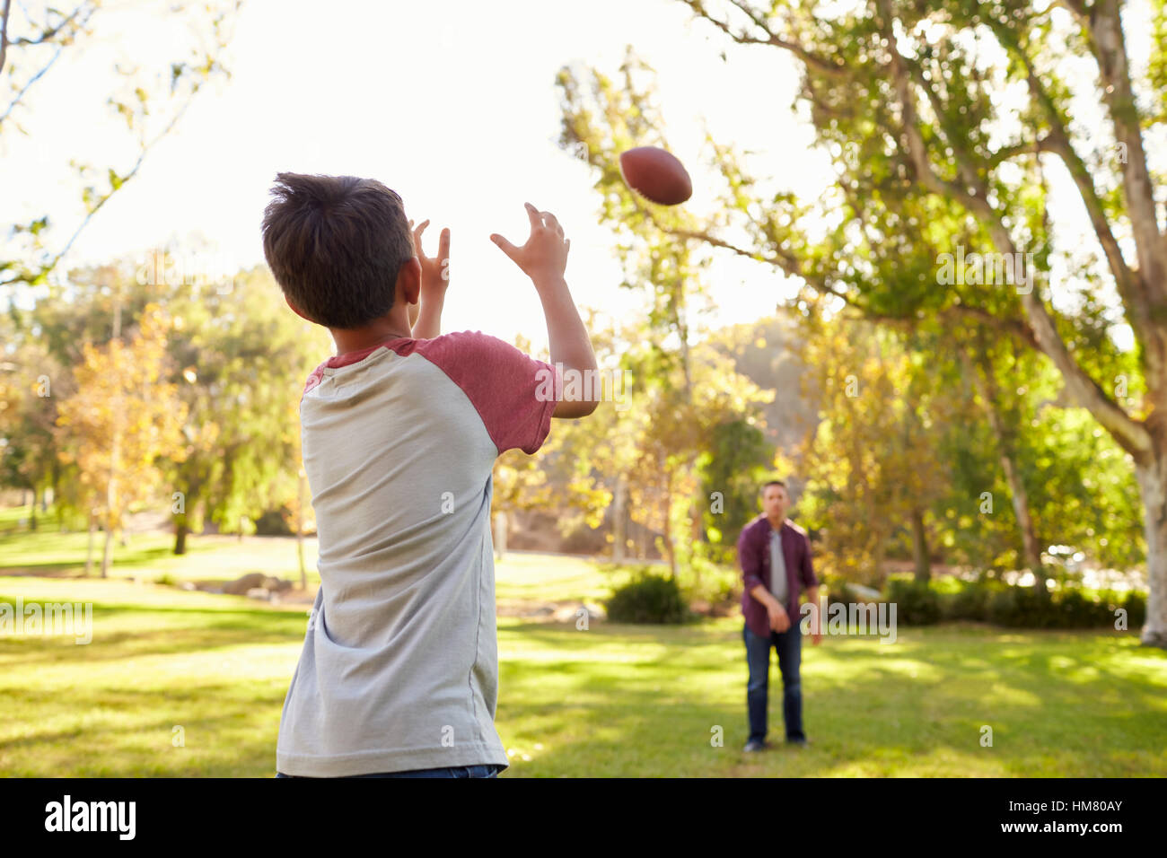 Dad and son throwing American football to each other in park Stock ...