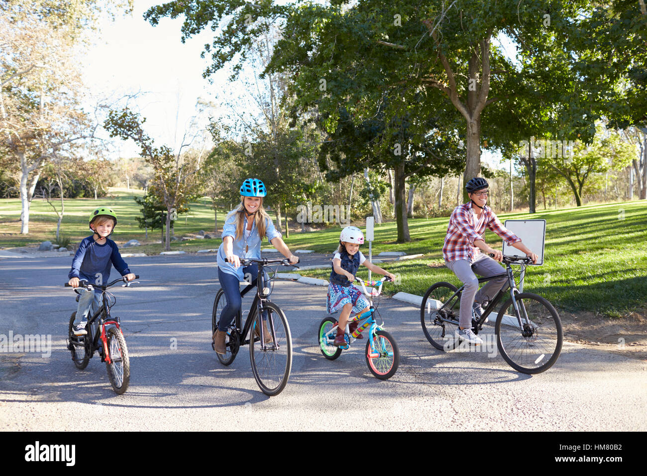Young white family cycling together through a park Stock Photo - Alamy
