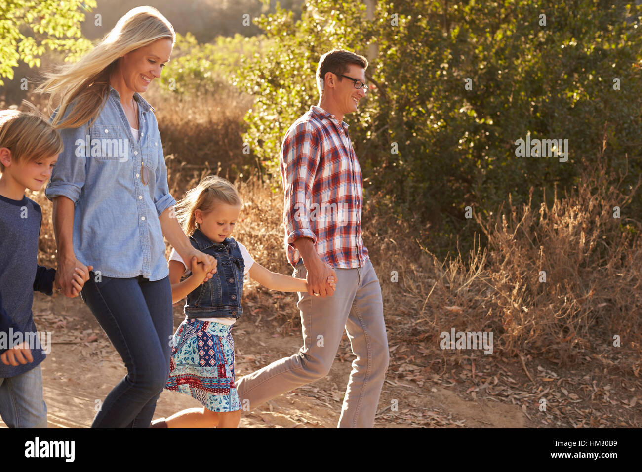 Young white family walking on a path in sunlight, side view Stock Photo ...