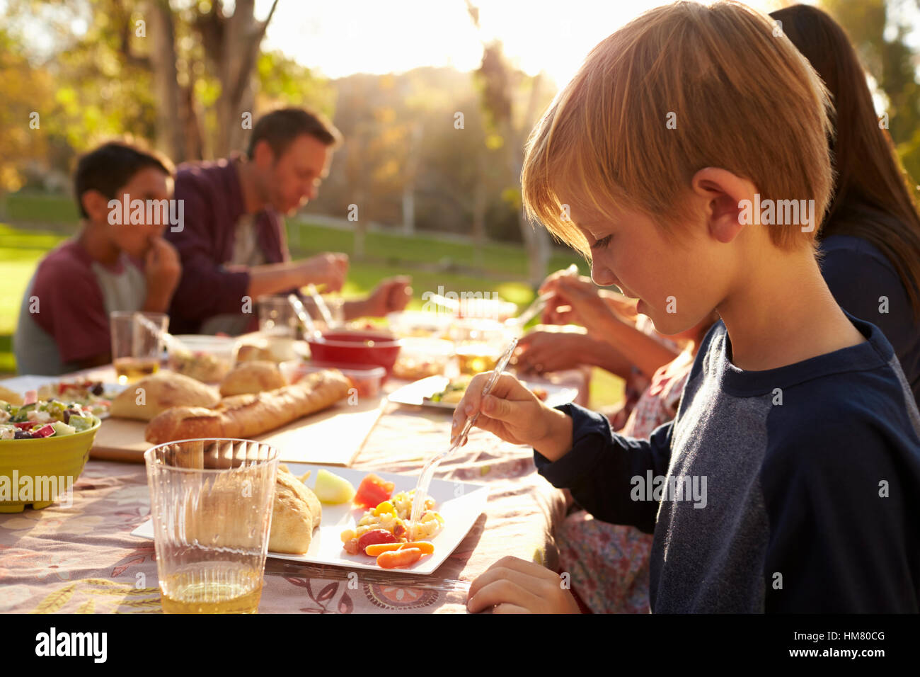 Young boy eating at a picnic table in a park Stock Photo - Alamy