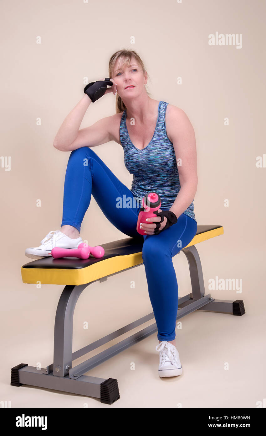 Woman sitting upright on a weightlifting bench in a gym Stock Photo - Alamy