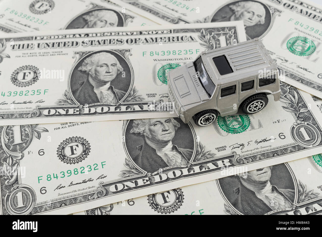 Small silver toy car on US 1 Dollar / 1 $ bills. As metaphor for the ...