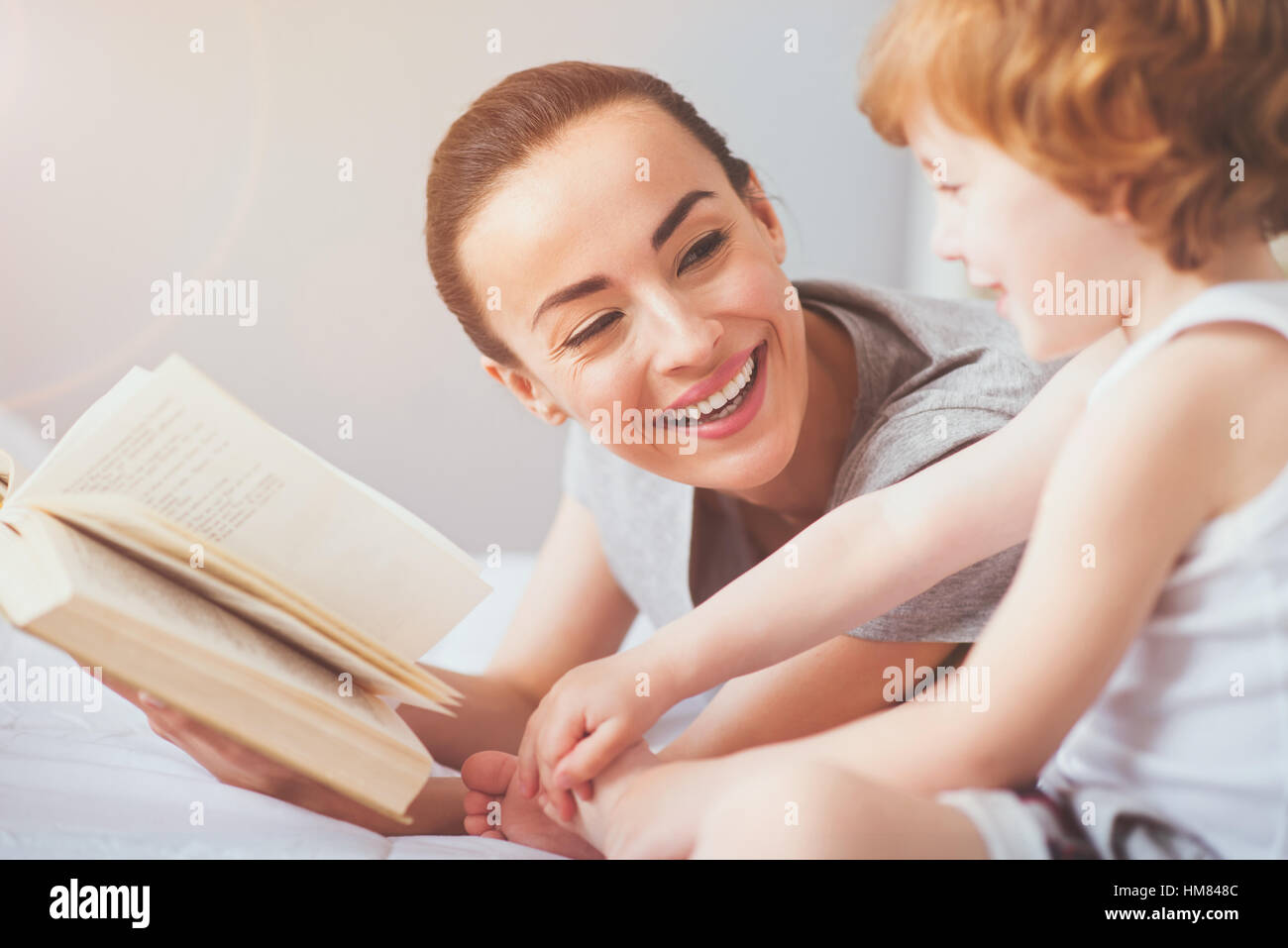 Laughing woman reading a book to her son Stock Photo - Alamy