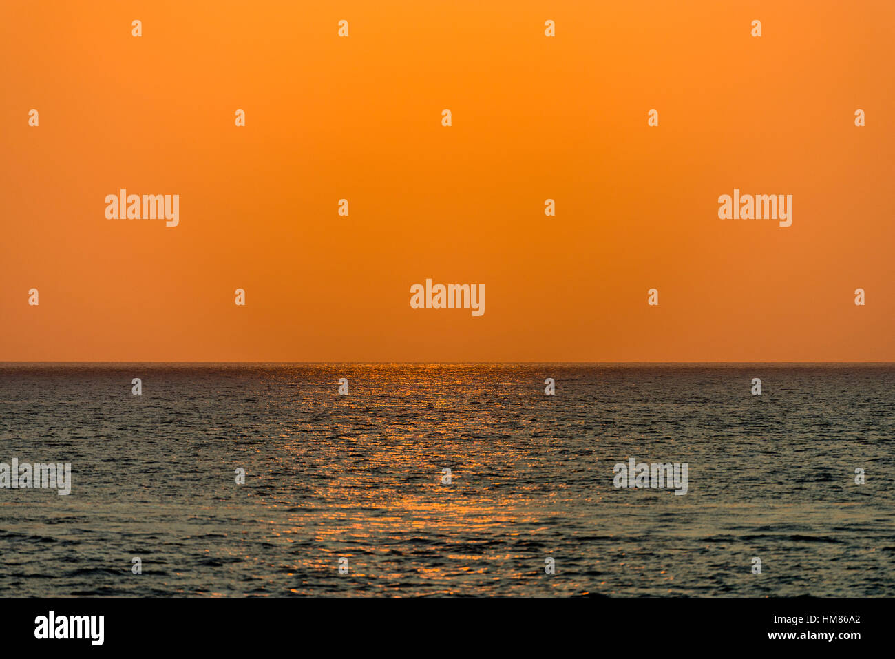 A featureless orange sky over a turquoise ocean at sunset Stock Photo ...