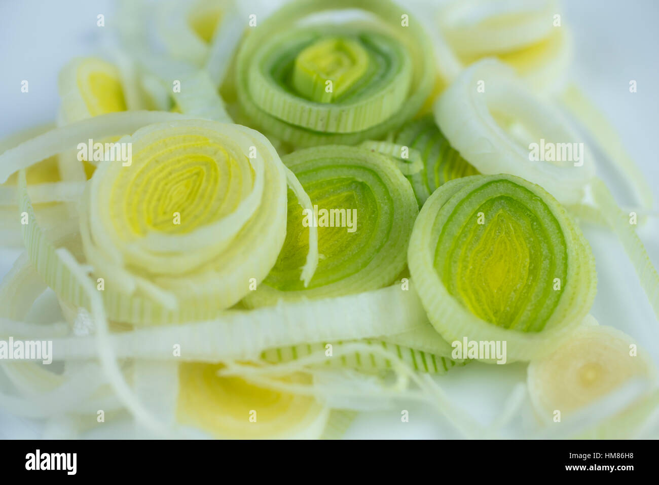 Leeks sliced in thin rings on a white plate to be used for an ...