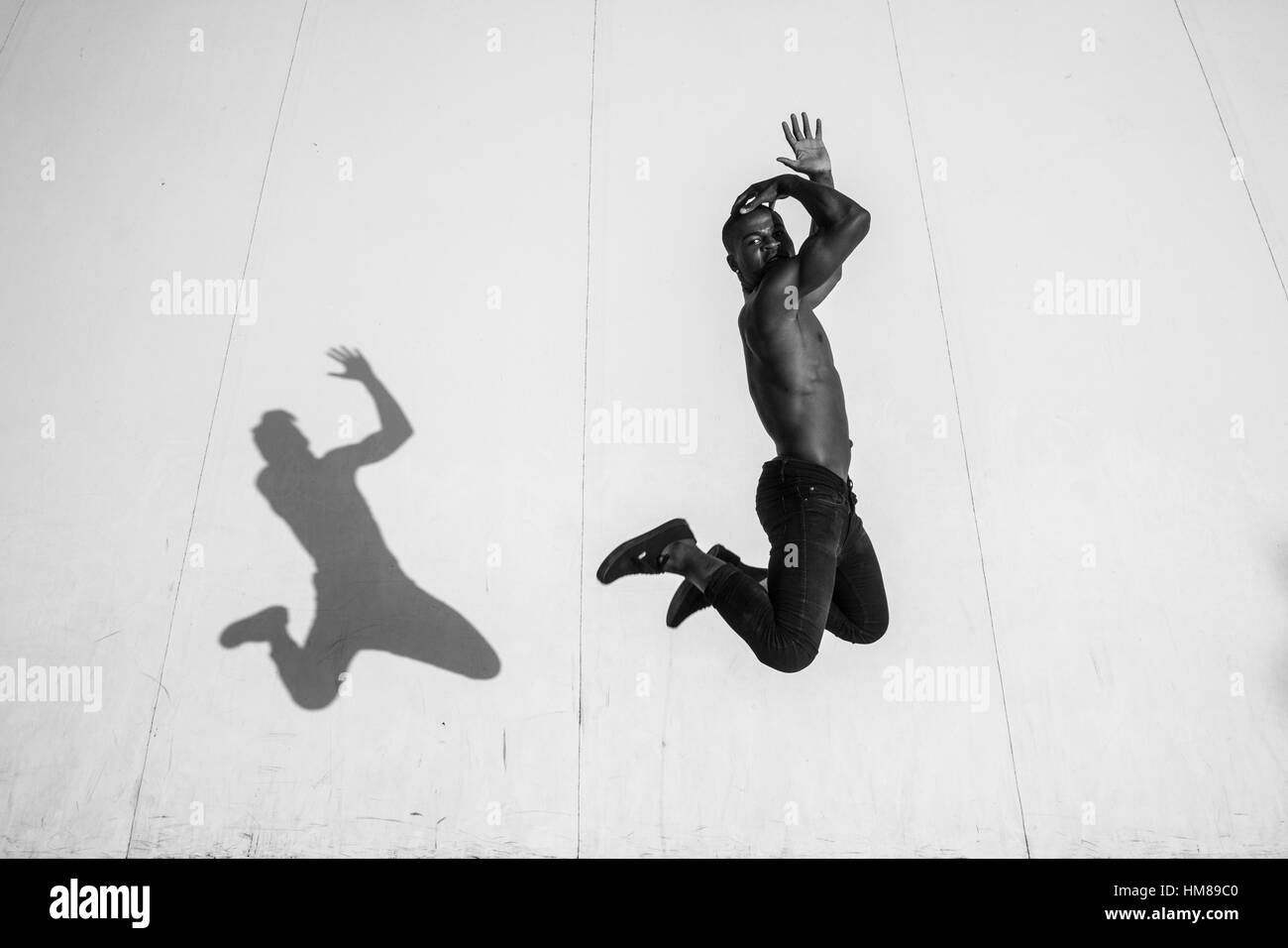 Portrait of Shirtless Young Adult Man Jumping with Shadow Cast Against ...