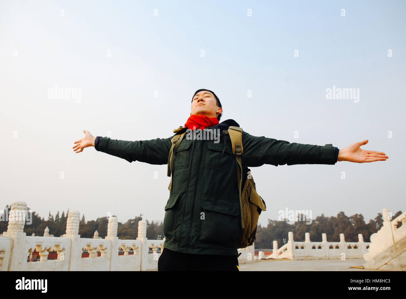 Asian man stretching arms wide open in Chinese architecture with blue ...