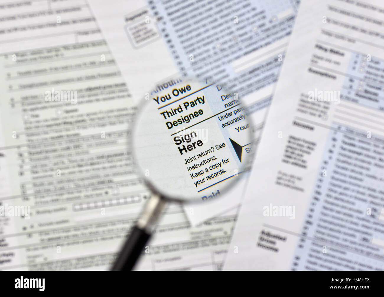 'Sign here' under magnifying glass on 1040 U.S individual income tax ...