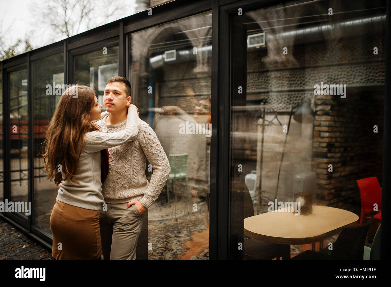 Young couple wearing on tied warm sweaters hugging in love background ...