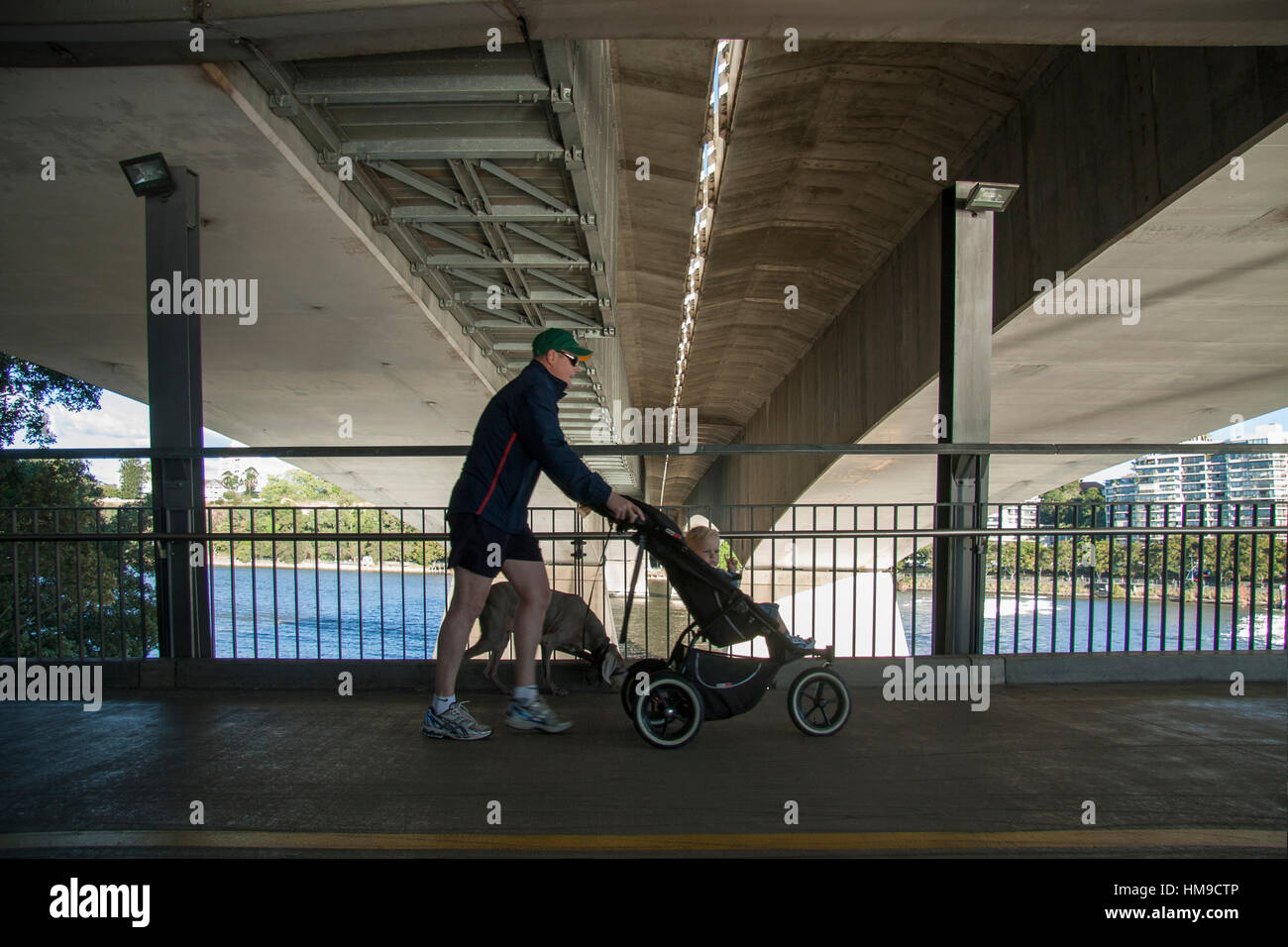 man pushing a baby in a buggy under a bridge Stock Photo - Alamy