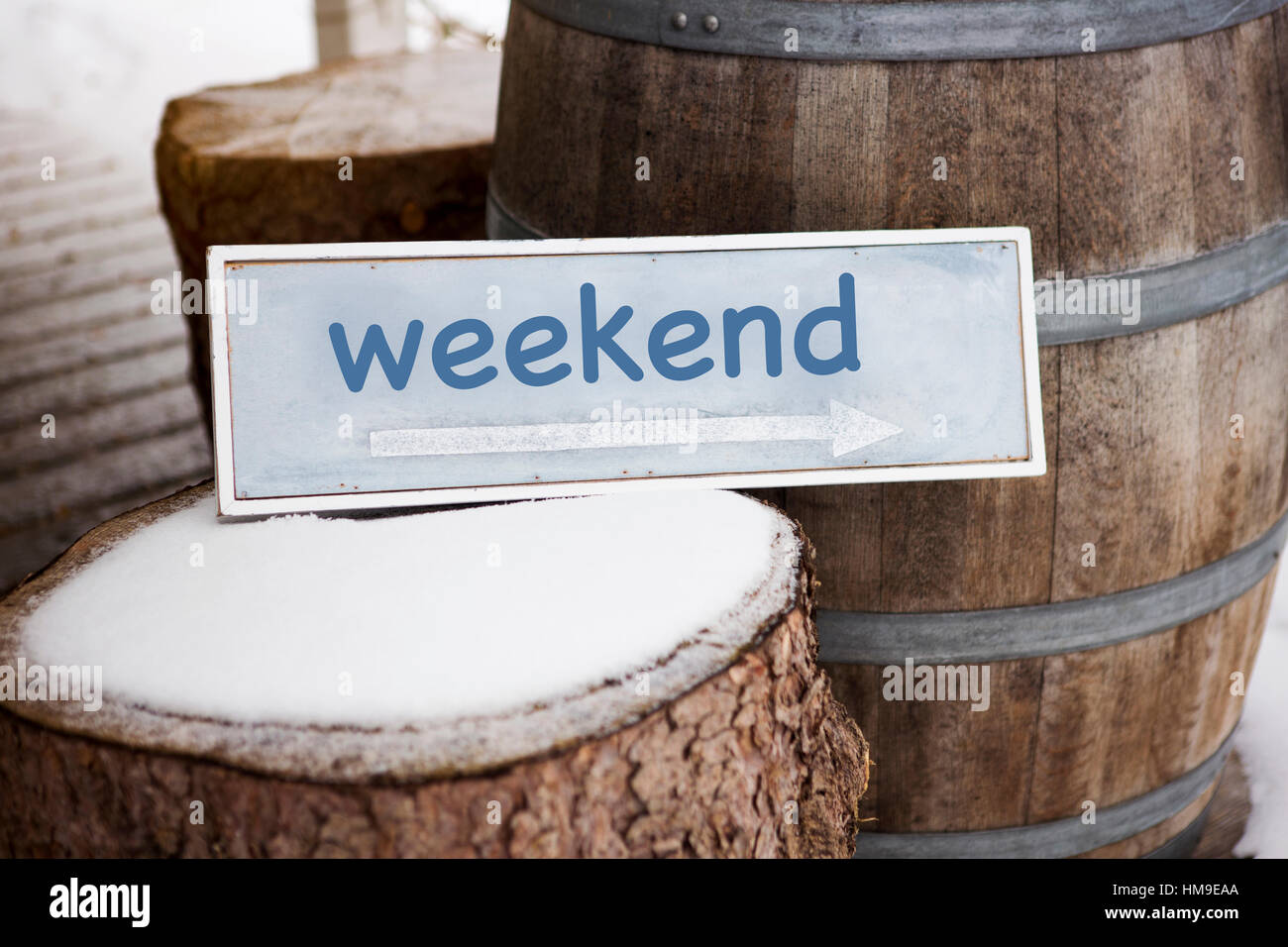 blue wooden sign with arrow on tree stump with the word Weekend written ...