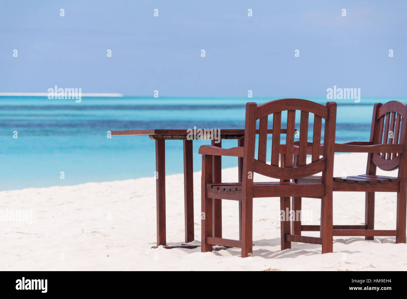 wooden table with two chairs on tropical beach with turquoise water in ...