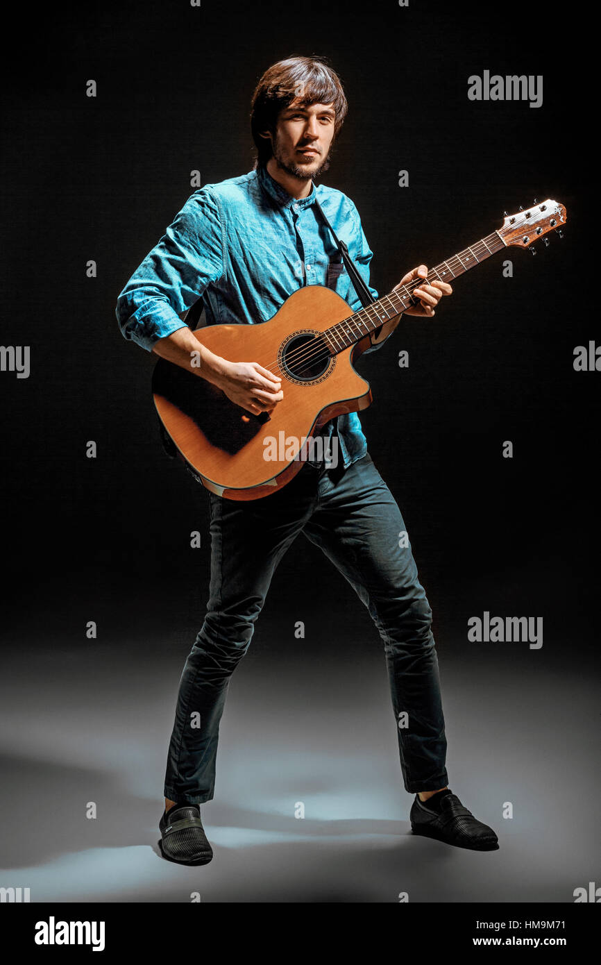 Cool guy standing with guitar on dark background Stock Photo - Alamy