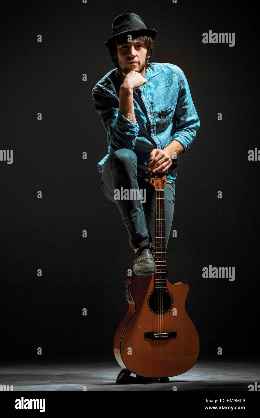 Cool guy standing with guitar on dark background Stock Photo - Alamy