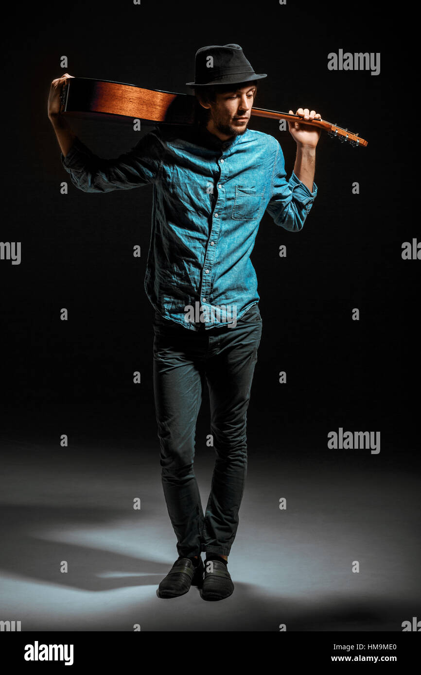 Cool guy standing with guitar on dark background Stock Photo - Alamy