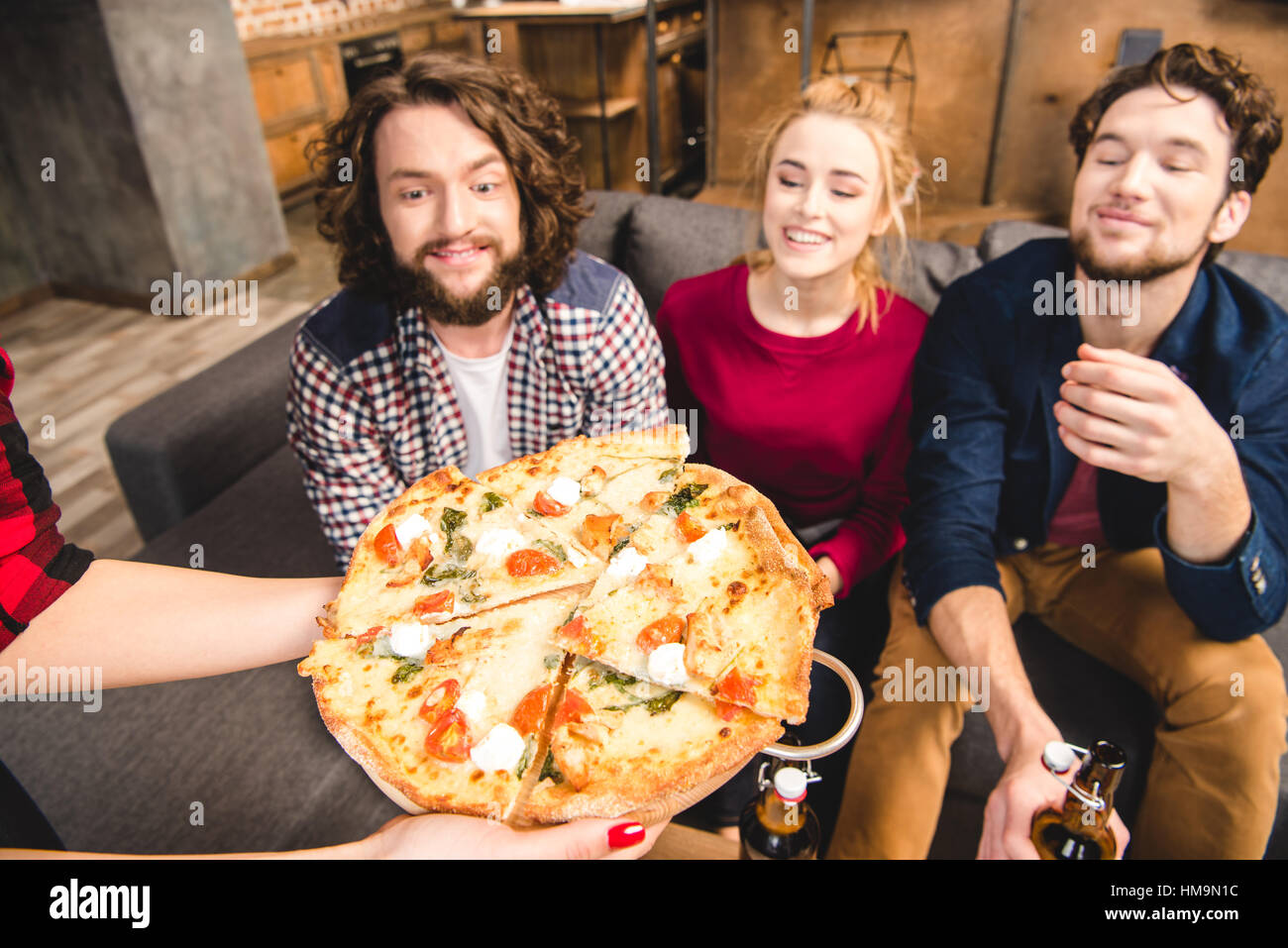 Smiling friends tasting pizza Stock Photo - Alamy