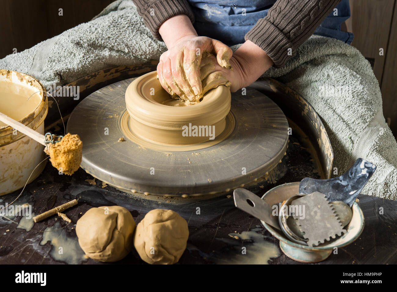 Ceramic workshop, hands shape clay on pottery wheel, tools at front ...