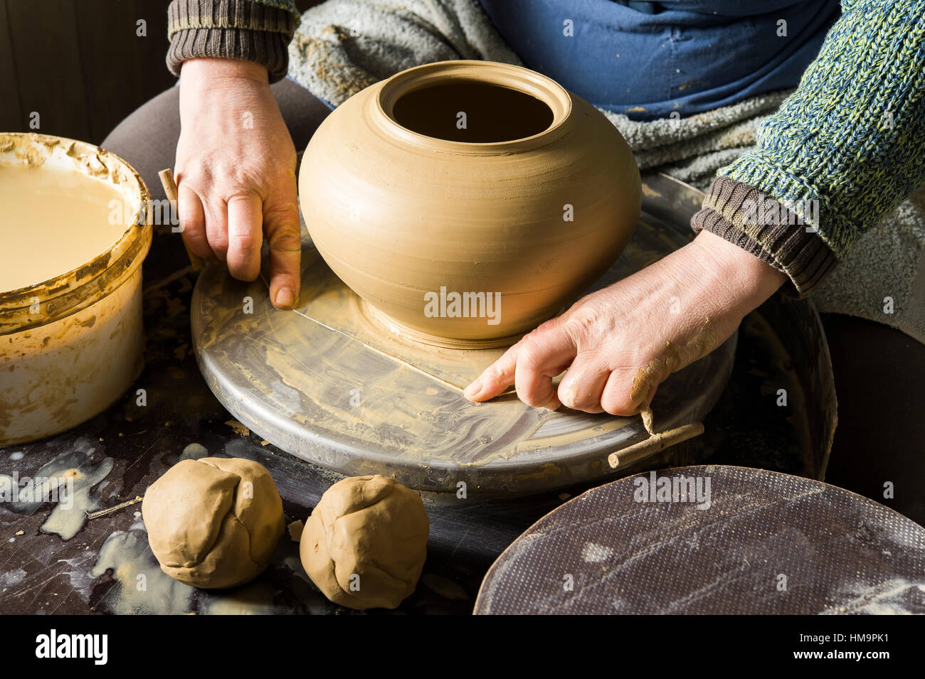 Ceramic workshop, hands separate clay with cutting wire from pottery ...