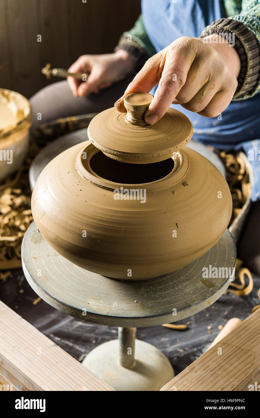 Ceramics workshop, hand holding lid on opening of can over pottery ...