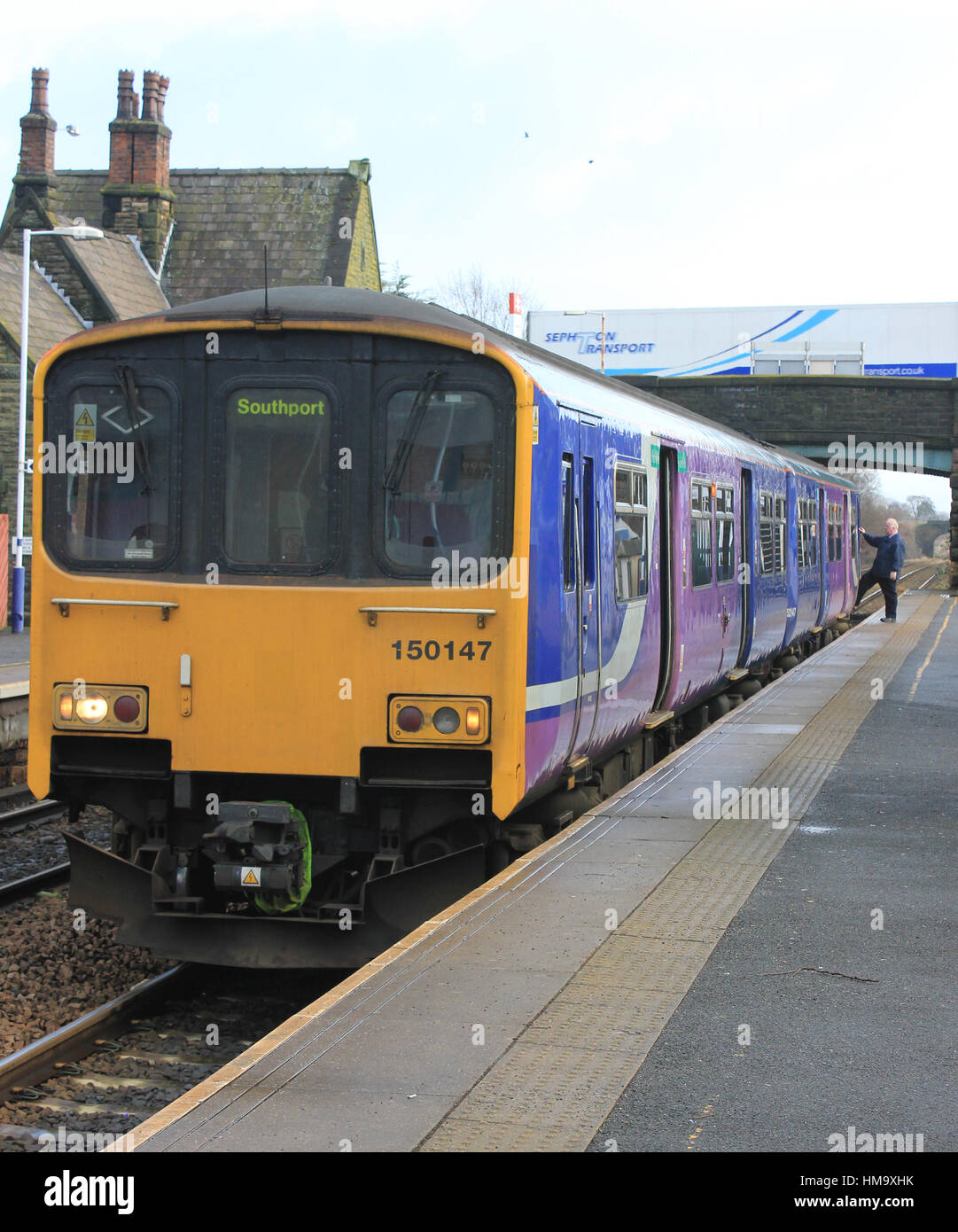 A guard, of a Northern train service rejoins his train at Burscough ...