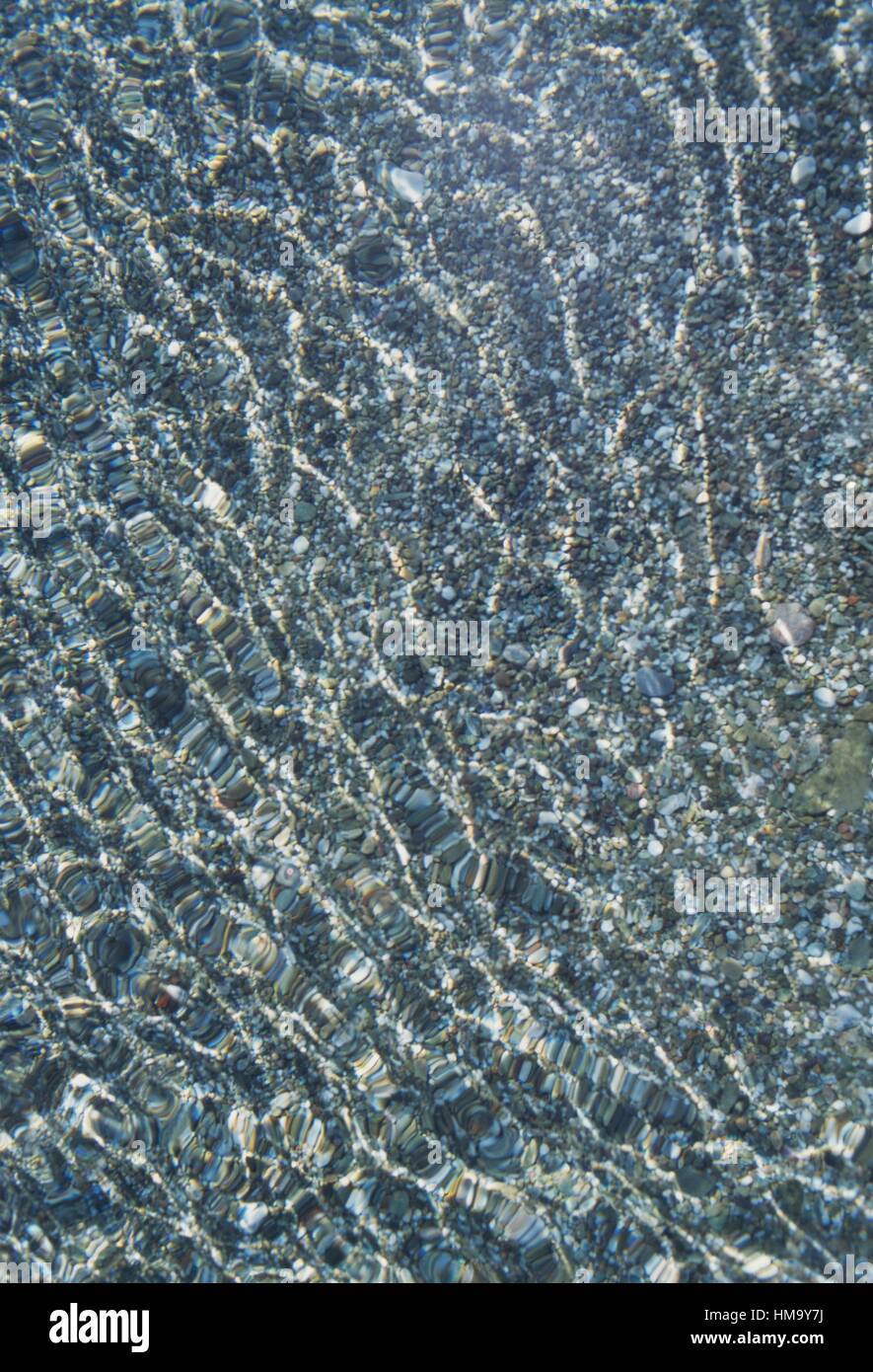 Water reflecting on a sea-bed with pebbles, near Itanos, Crete, Greece ...
