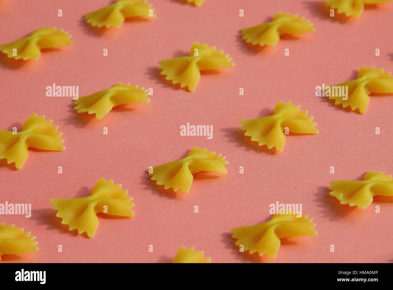 Makaroni or pasta bow shape in row on pink background Stock Photo - Alamy
