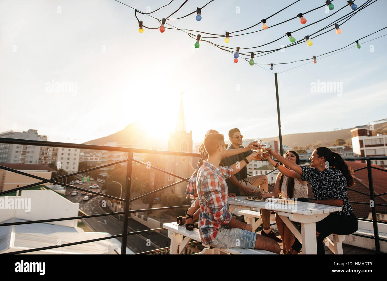 Outdoor shot of young people toasting drinks at a rooftop party. Young ...