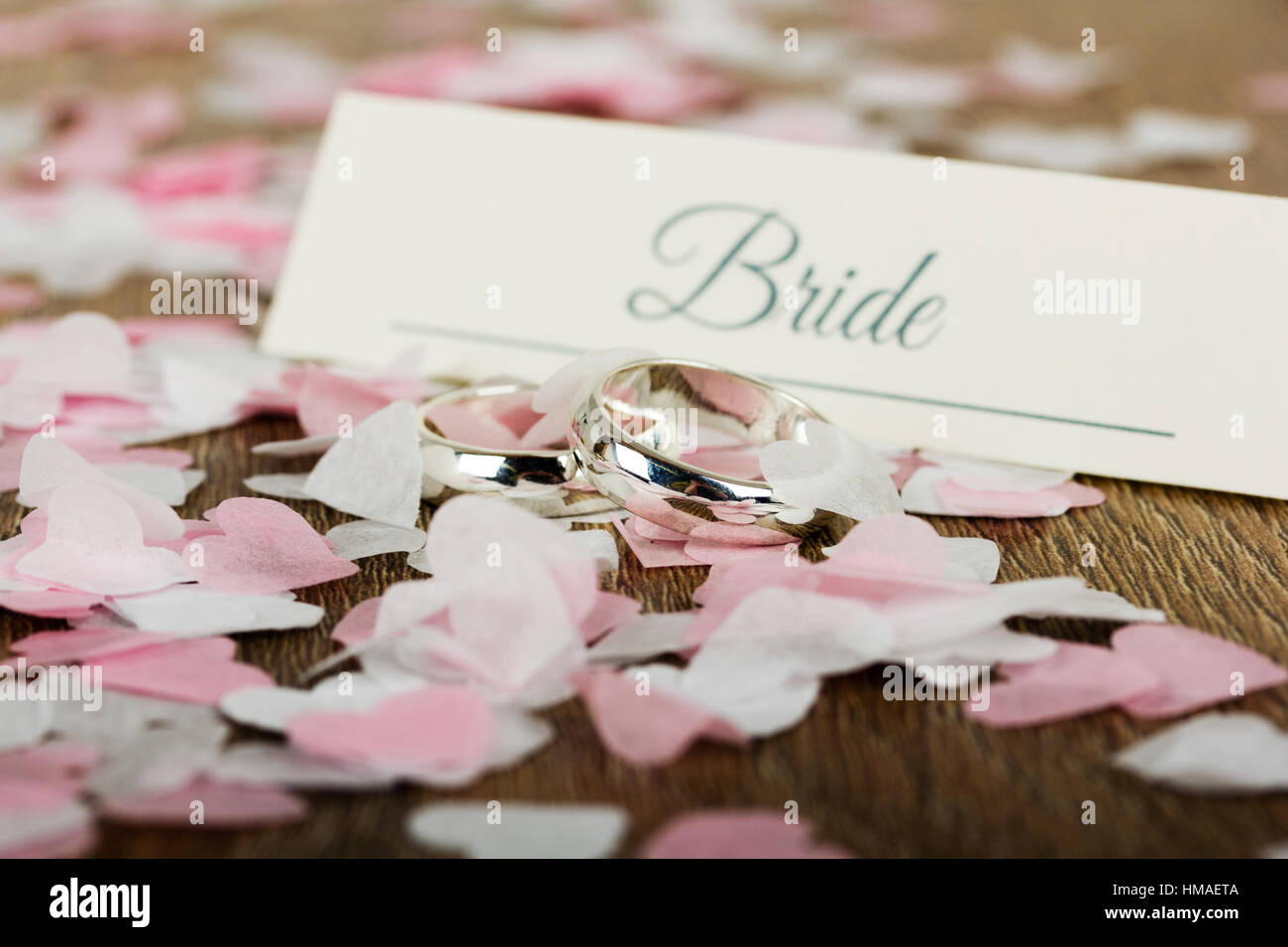 pair of white gold wedding rings on a wooden background with confetti ...