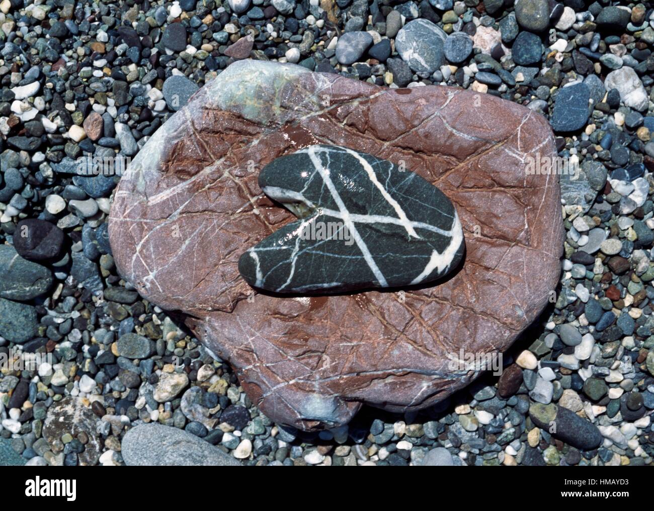 Black rock with white lines and grey rock with signs of erosion ...