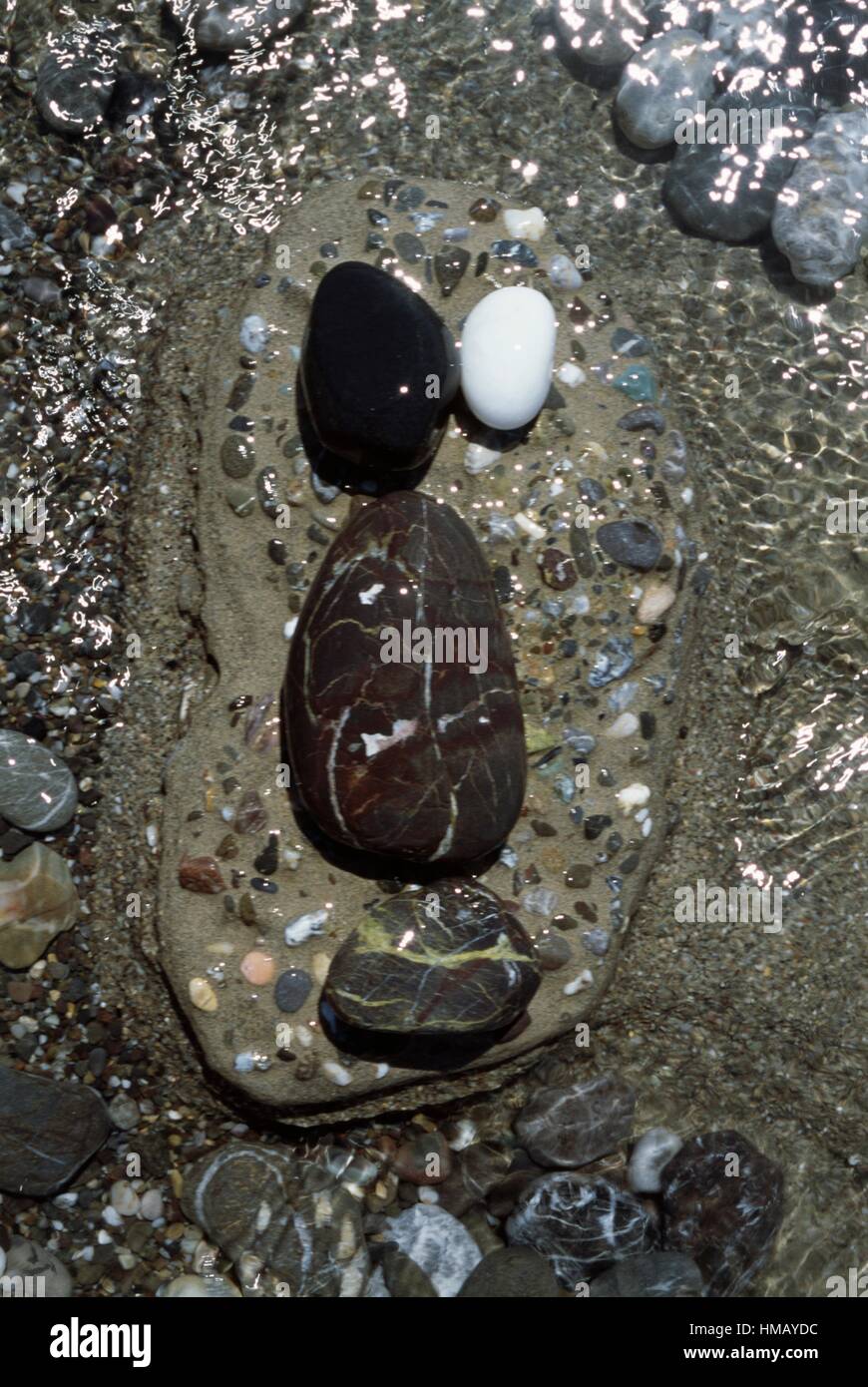Sea water lapping white and black rocks on the beach, Keratokambos ...