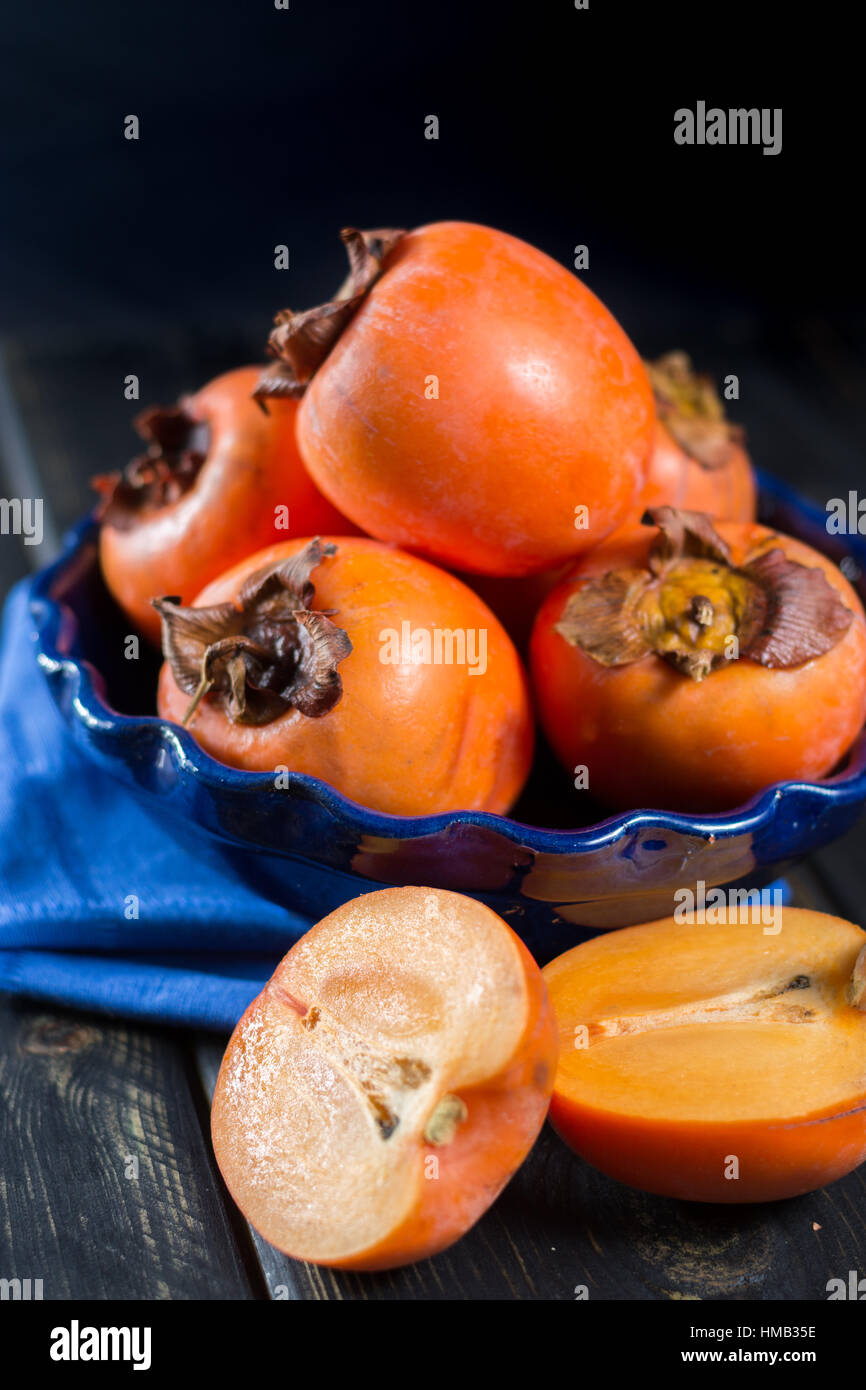 Ripe orange hachiya persimmons in blue bowl Stock Photo - Alamy