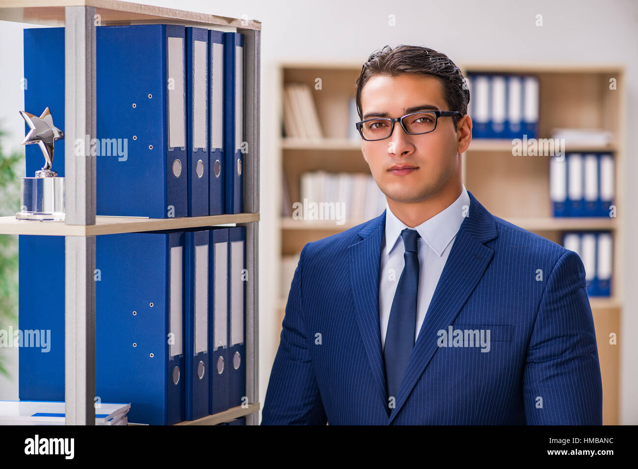 Young man standing next to the shelf with folders Stock Photo - Alamy