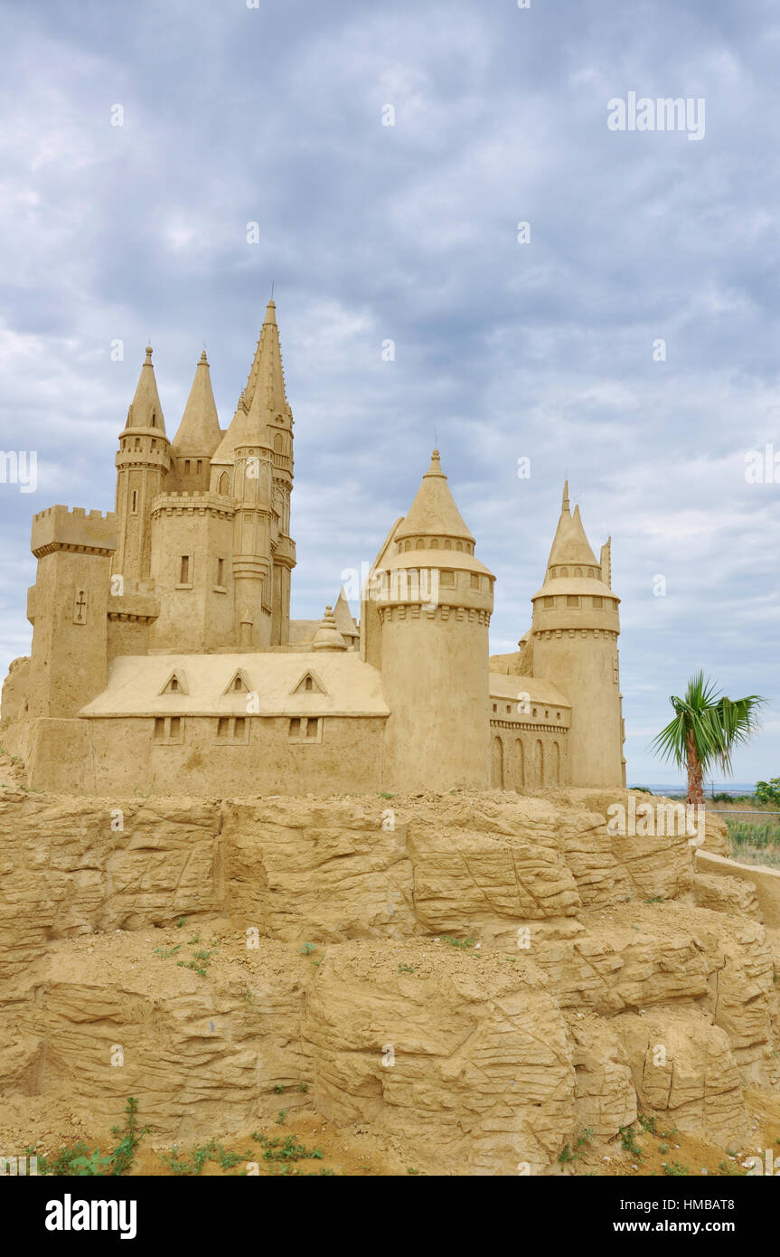 Sand castle sculpture with cloudy sky and small palm tree Stock Photo ...