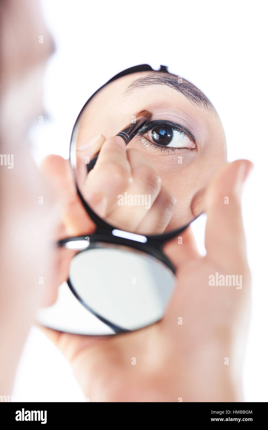 girl put make up on eye close up reflection in mirror isolated on white ...