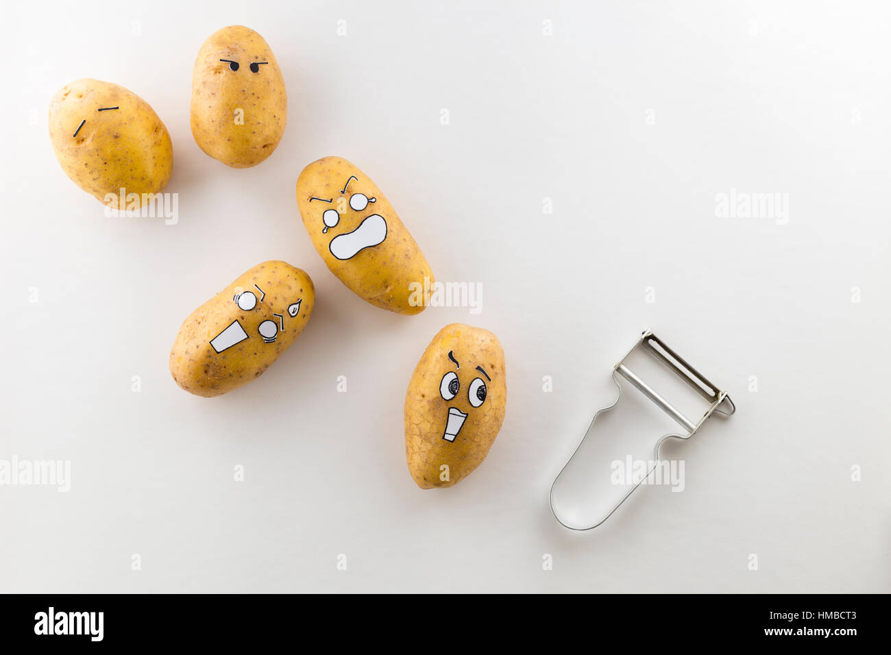 Fresh potatoes with cartoon style faces laying on white surface are ...