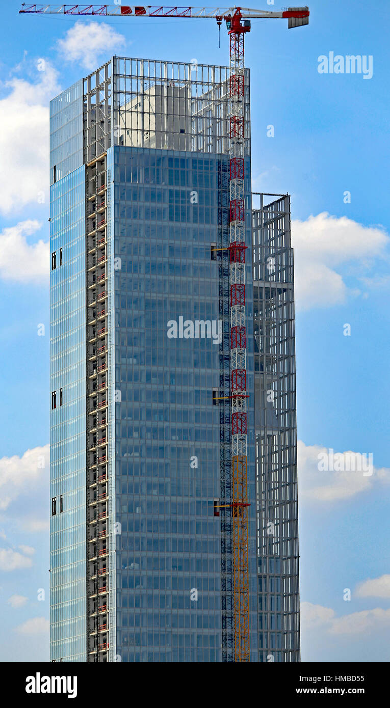 skyscraper under construction made of glass and steel with a huge crane ...