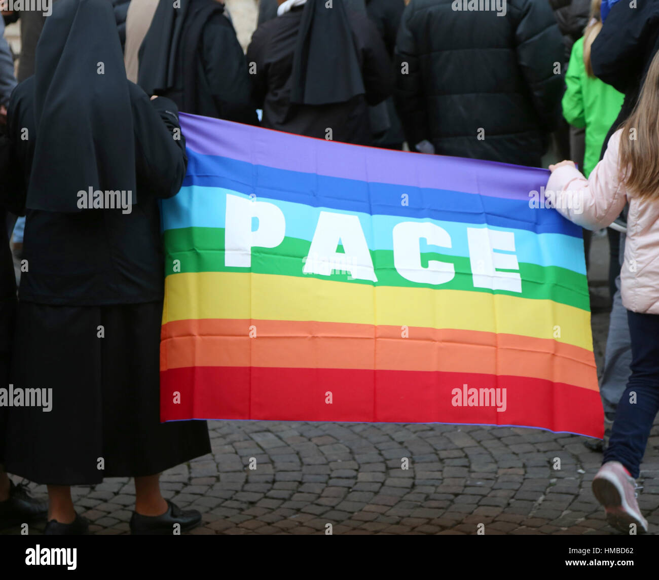 nun with a black veil and a little girl holding the colorful flag with ...