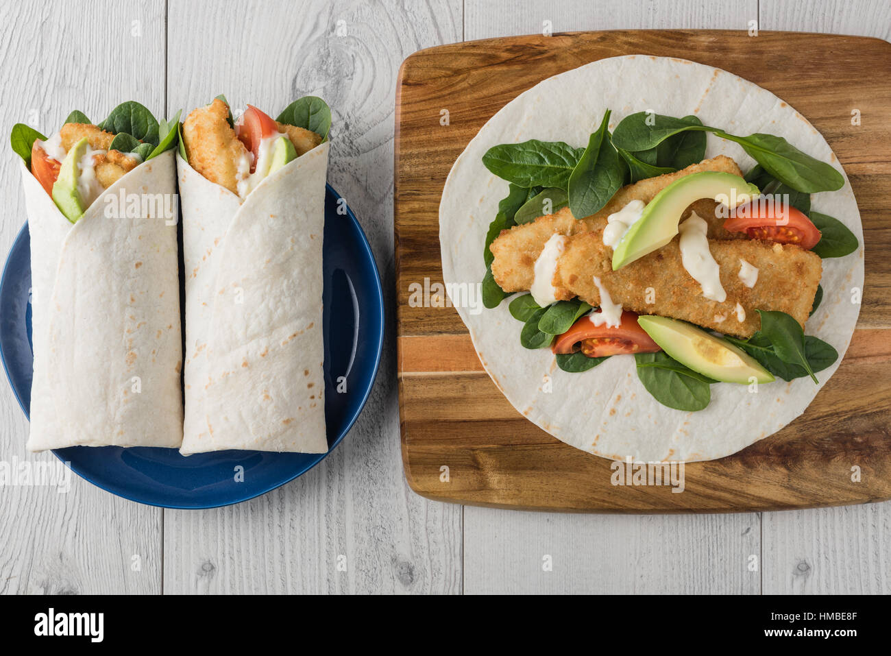 Fish finger wraps with avocado and tomato serves on wooden cheese ...