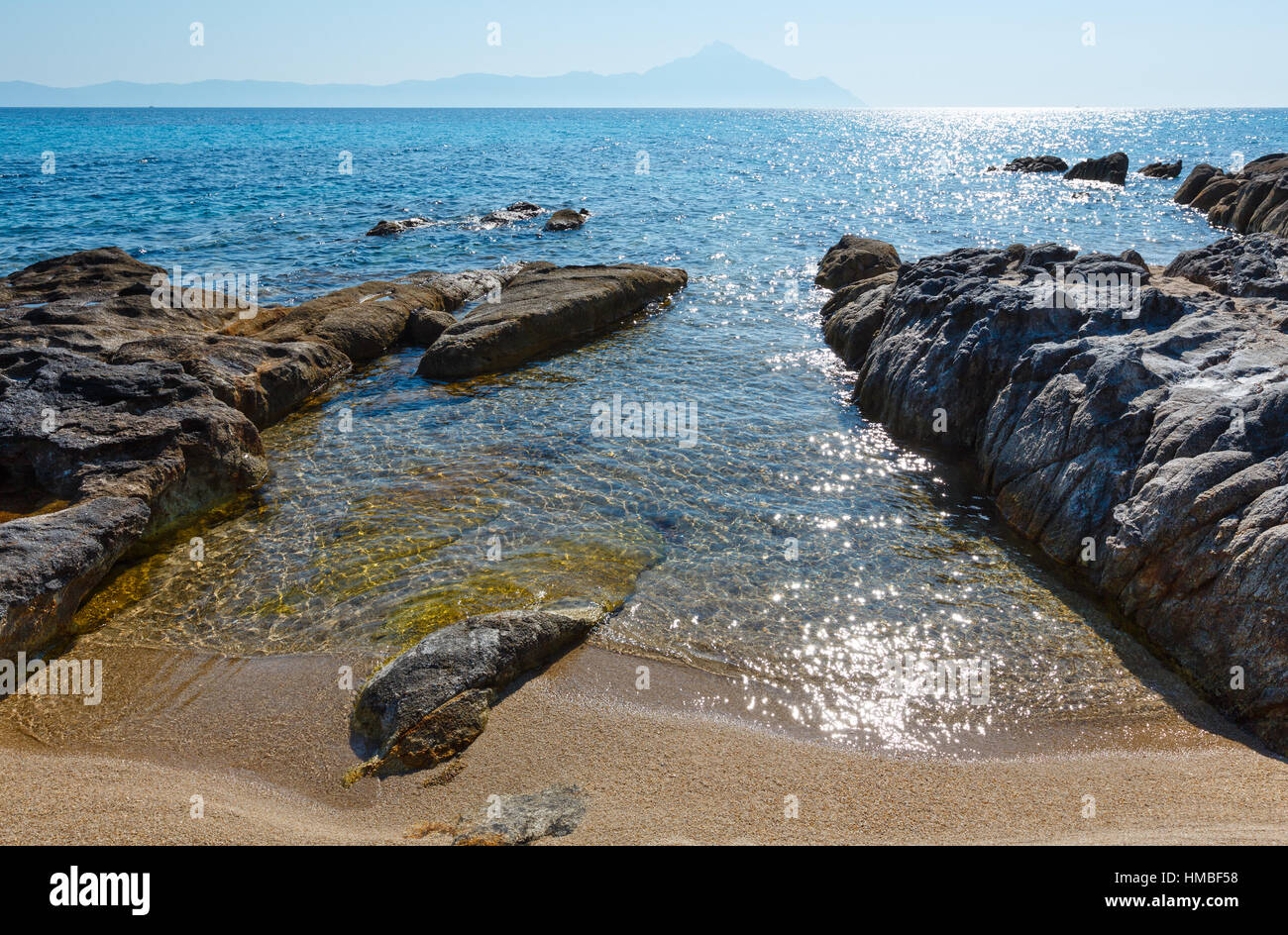 Morning sun reflection on sea water surface and rocky coast near ...